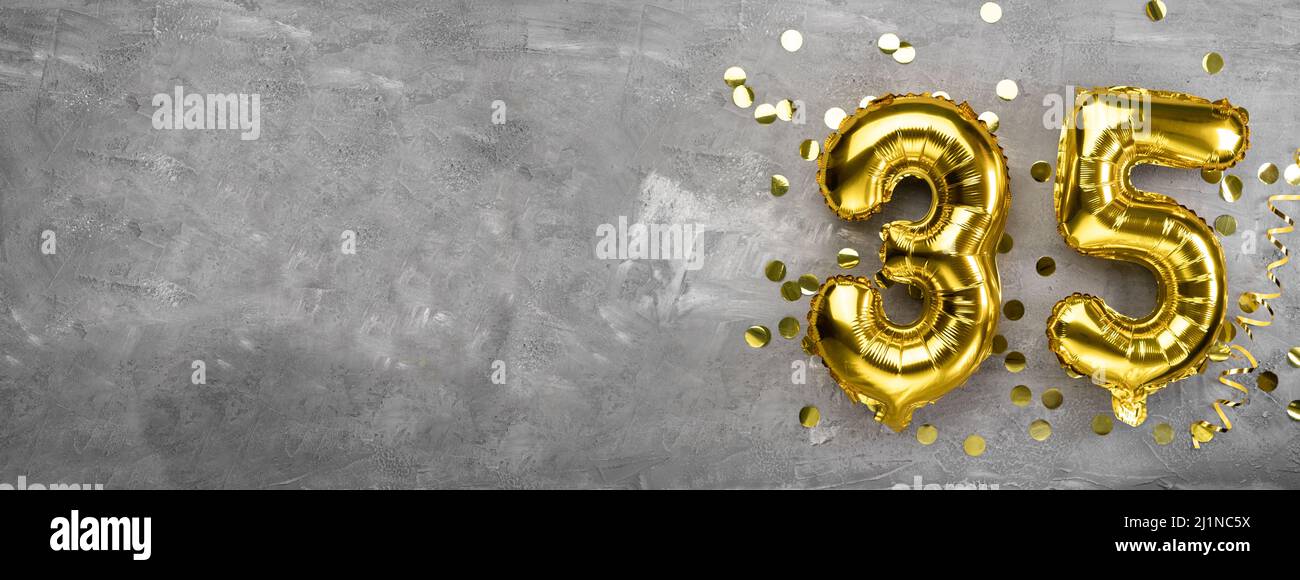 Yellow foil balloon number, number thirty-five on a concrete background ...