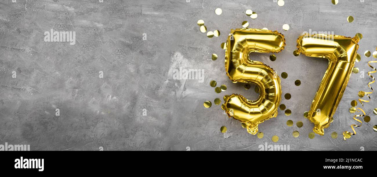 Yellow foil balloon number, number fifty seven concrete background ...