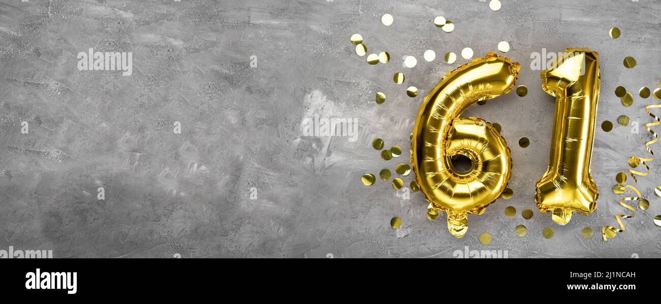 Yellow foil balloon number, number sixty one on a concrete background ...