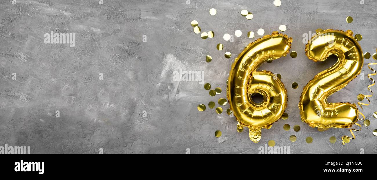 Yellow foil balloon number, number sixty two on a concrete background ...