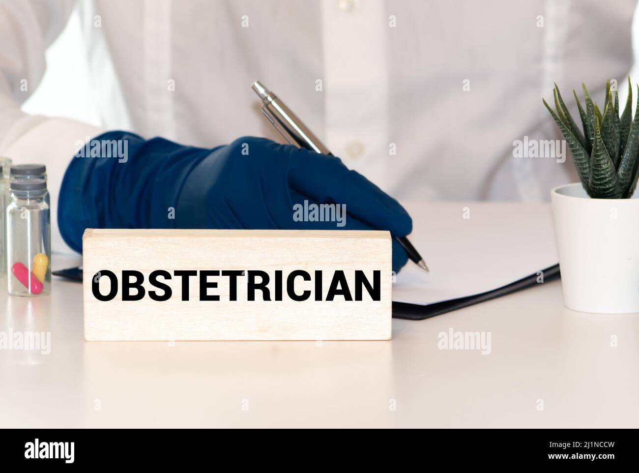 Card with word Obstetrician, menstrual pad and birth control pills on ...