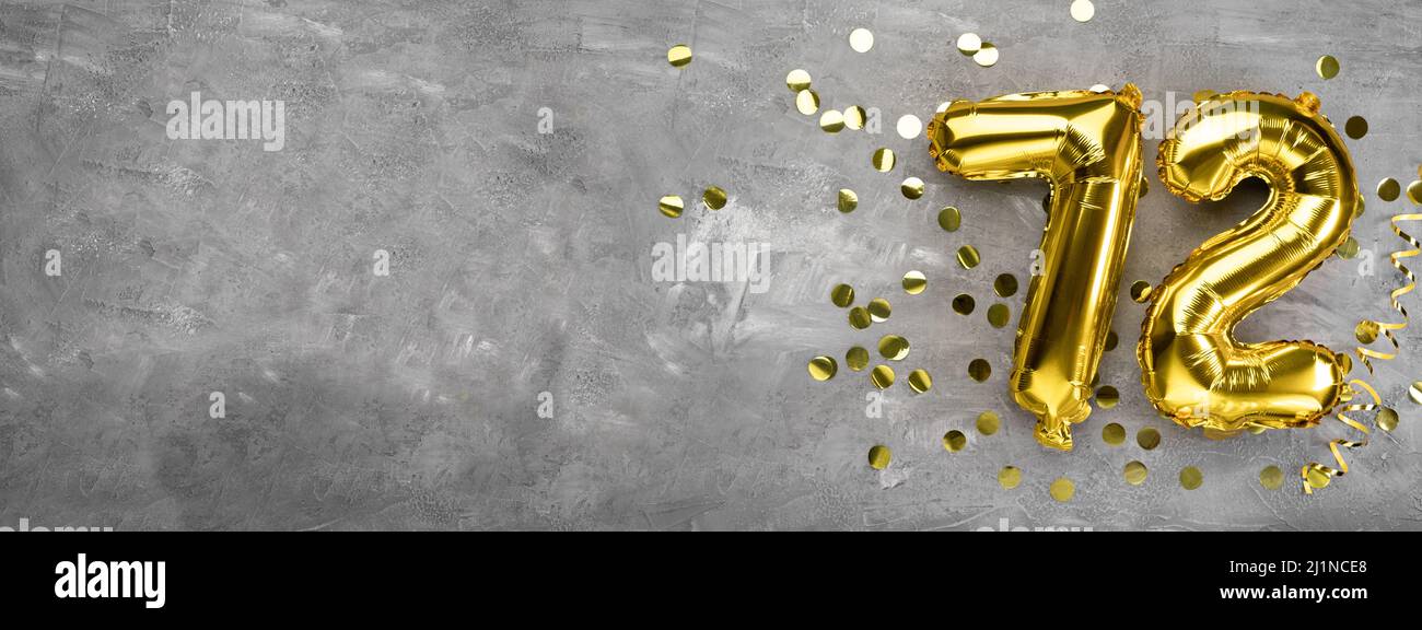 Yellow foil balloon number, number seventy two on a concrete background ...