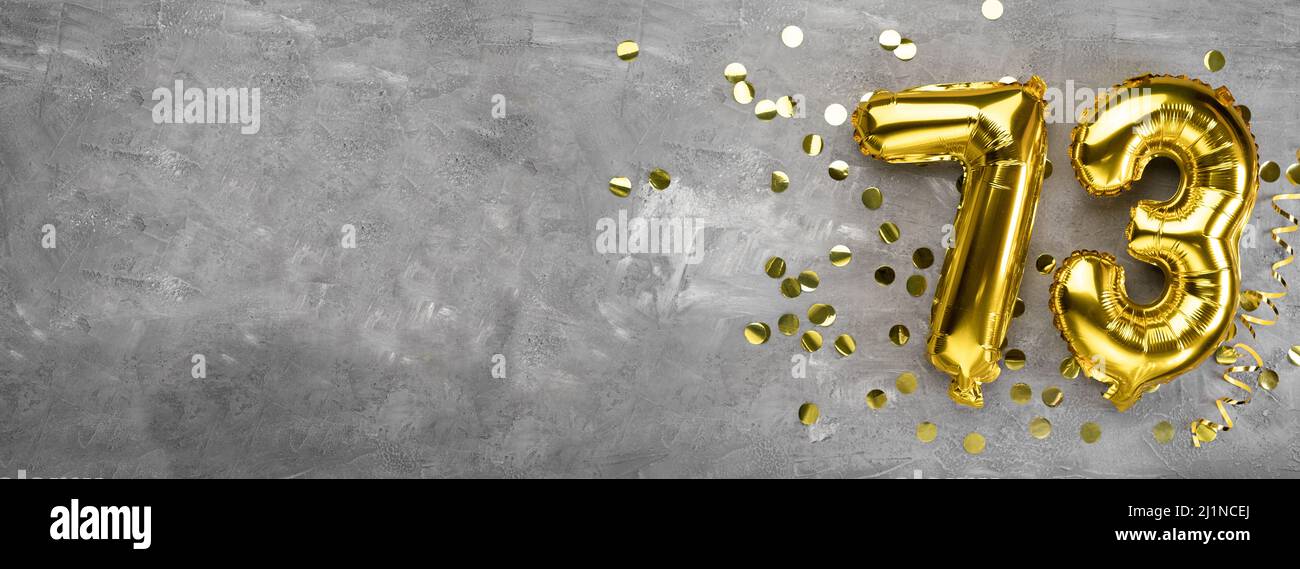 Yellow foil balloon number, number seventy three on a concrete ...