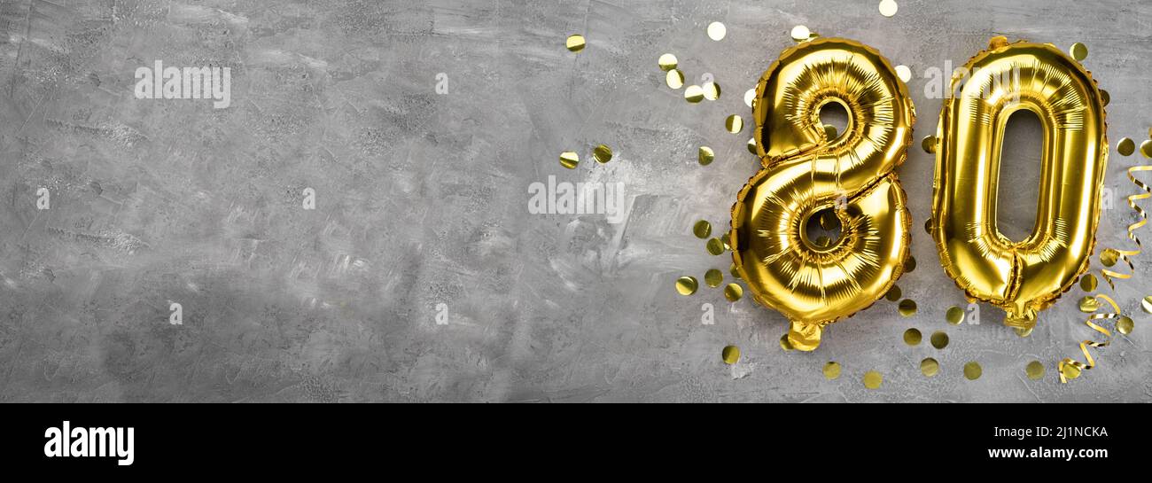Yellow foil balloon number, number eighty on a concrete background ...