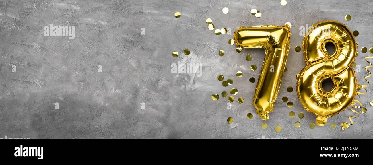 Yellow foil balloon number, number seventy-eight on a concrete ...