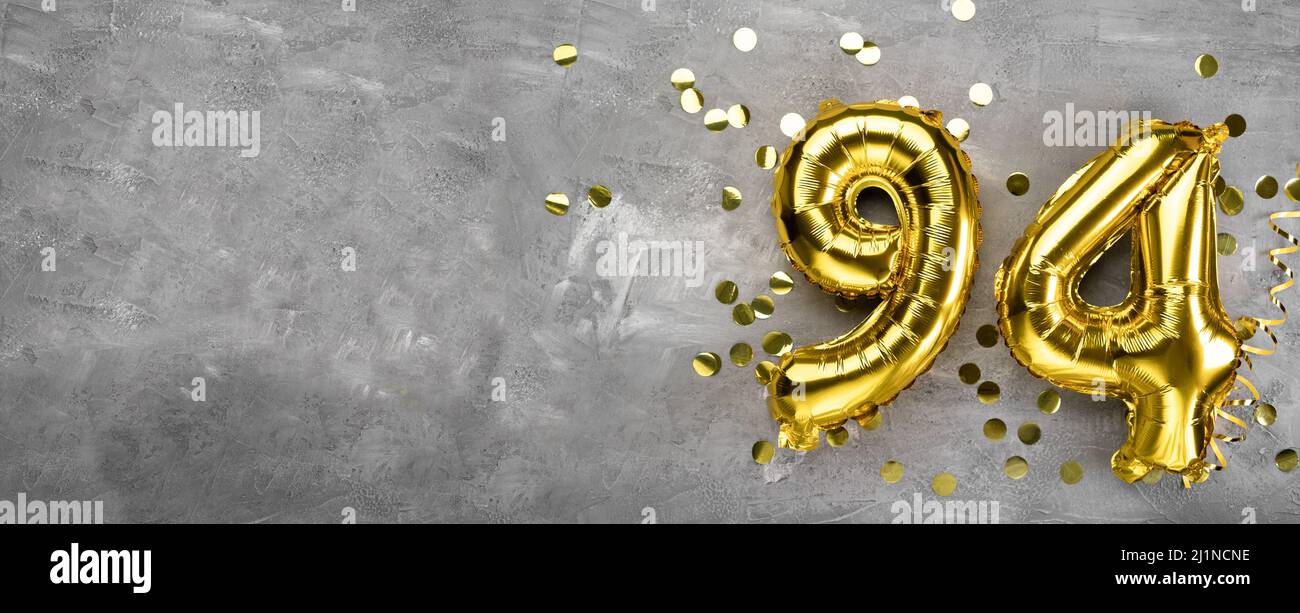 Yellow foil balloon number, number ninety-four on a concrete background ...