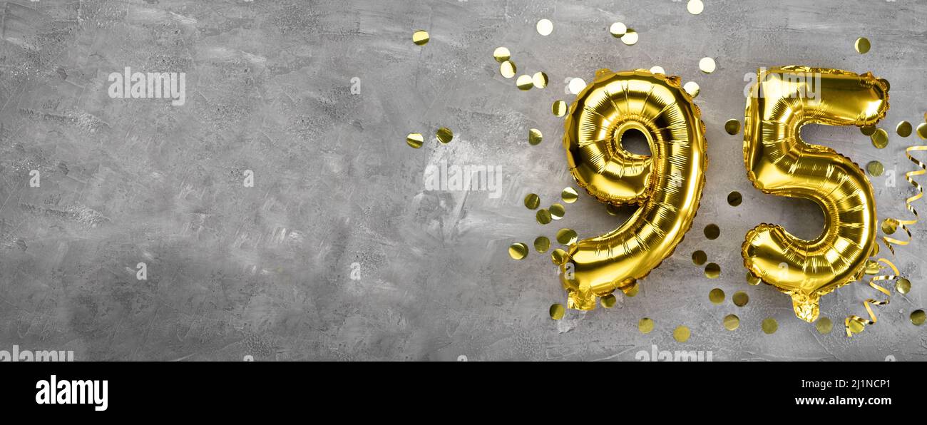 Yellow foil balloon number, number ninety-five on a concrete background ...