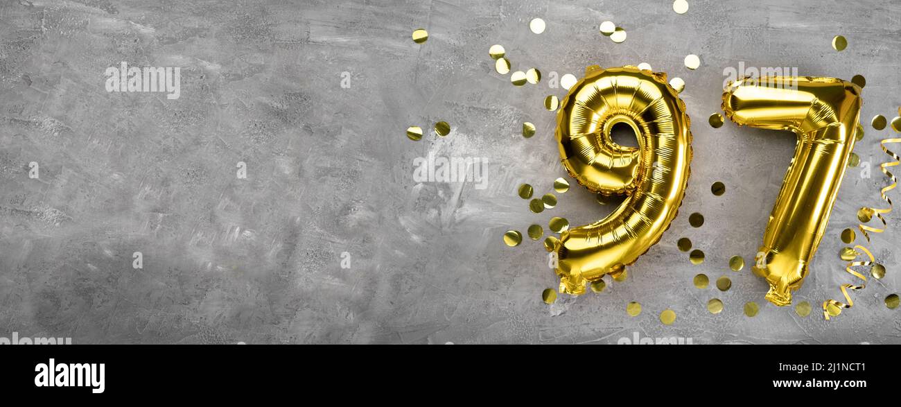 Yellow foil balloon number, number ninety-seven on a concrete background. Greeting card with the ...