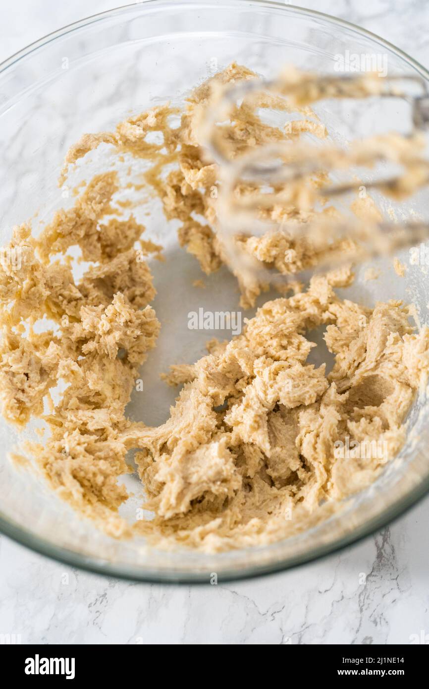 Mixing ingredients with a hand mixer in a large mixing bowl to bake ...