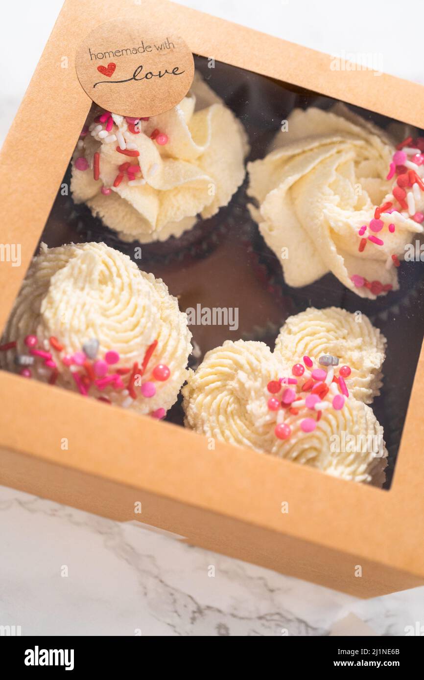 Packaging freshly baked red velvet cupcakes with white chocolate ...