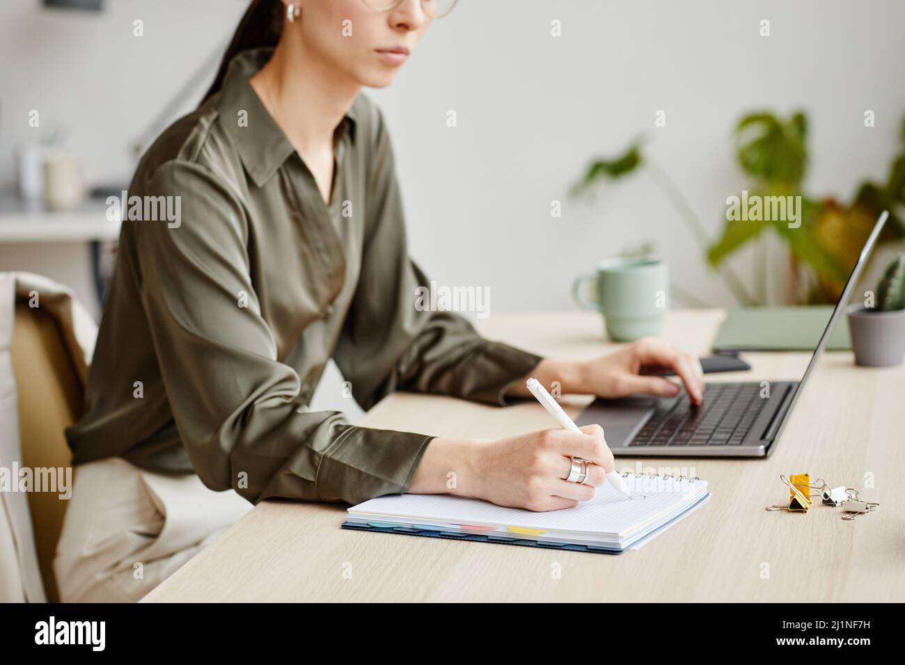 Side view portrait of female business owner writing in notebook while ...
