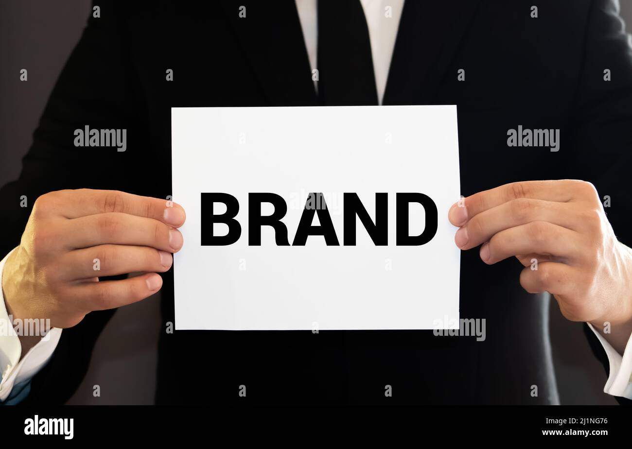 One hand holding the word brand over a beige background. Branding ...