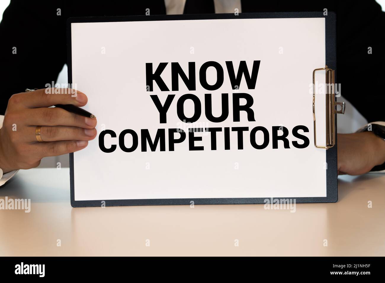 Closeup on businessman holding a card with text KNOW YOUR COMPETITORS ...
