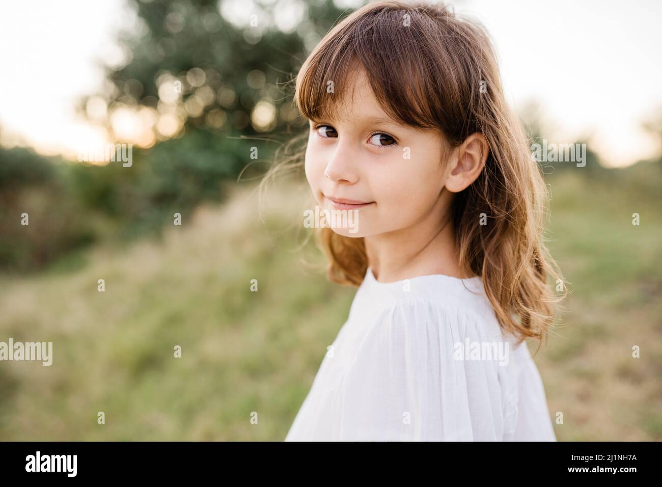 Portrait Of Beautiful Six Year Old Girl Standing In Field Sunset In
