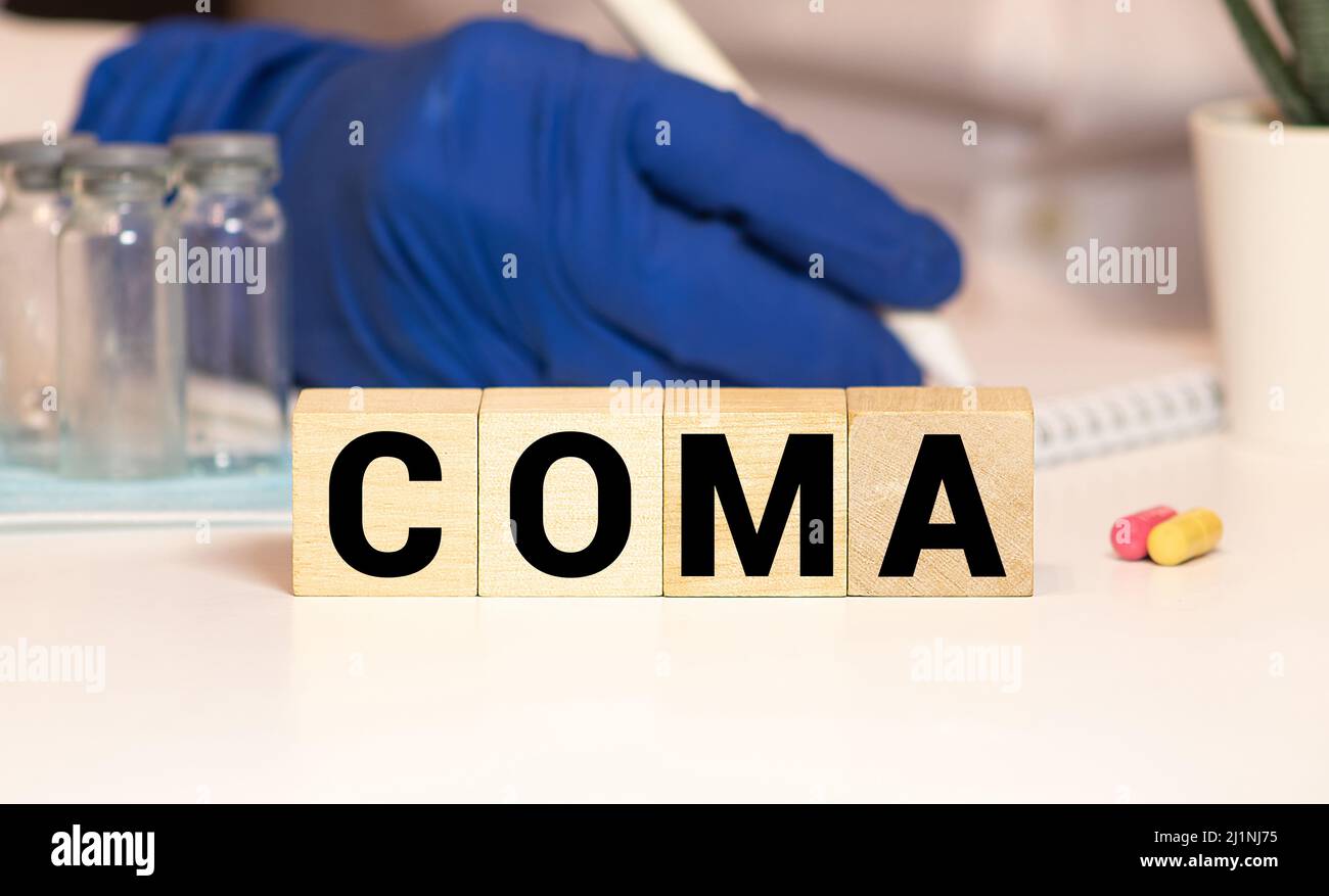 Coma - word from wooden blocks with letters, the complete absence of ...