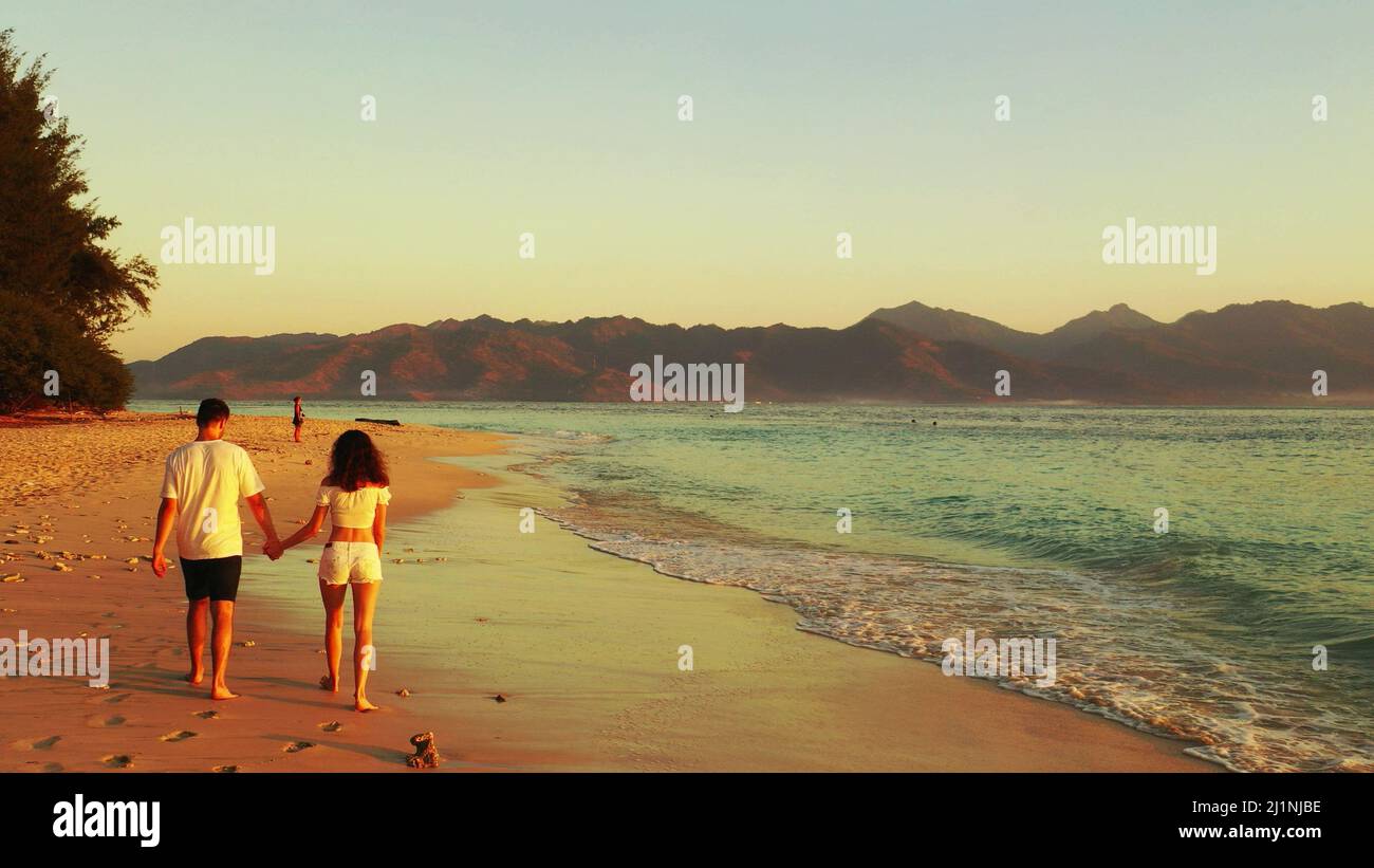 A romantic couple enjoying their time together on the beach at sunset, Gili Islands, Indonesia ...
