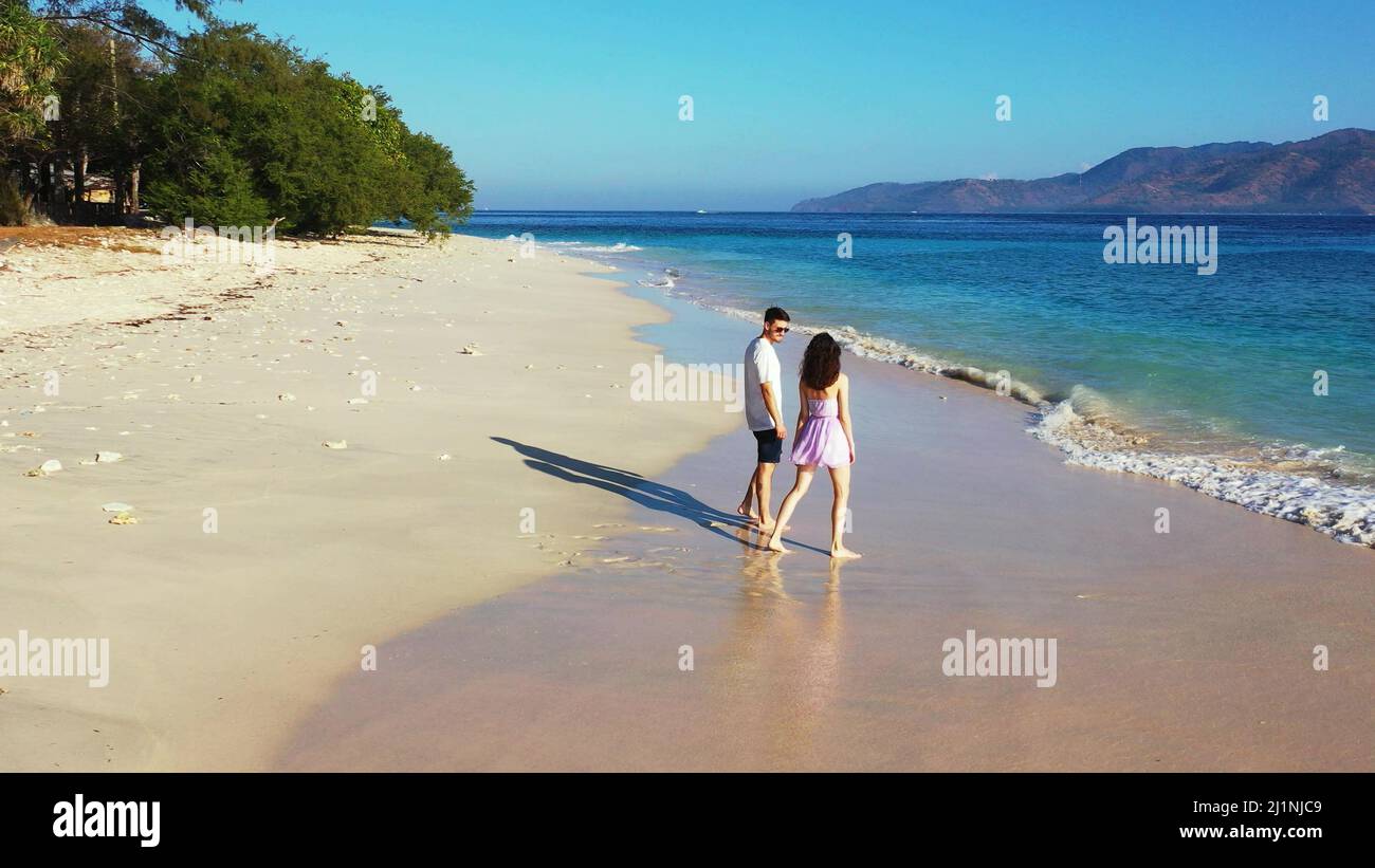 A romantic couple enjoying their time together on the beach on a sunny day, Gili Islands ...