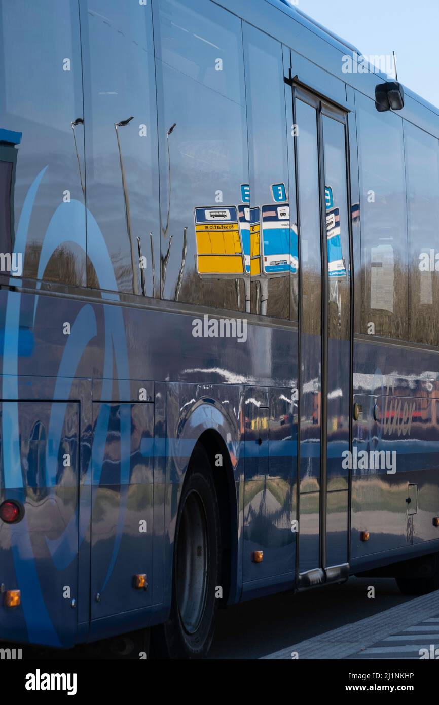 Reflections of signs in the shiny metal and glass of a blue Qliner ...