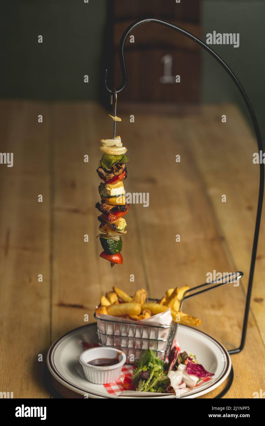 A Closeup of a hanging kebab ( grilled meat with vegetables ) served ...