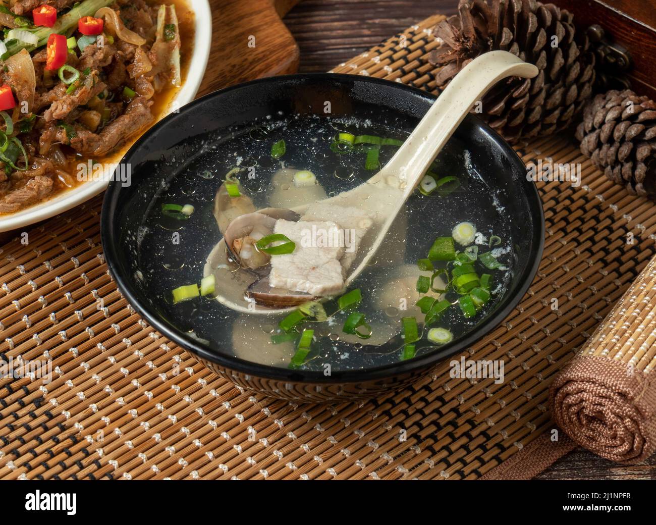 Red meat clam soup in a dish isolated on mat side view on dark wooden ...