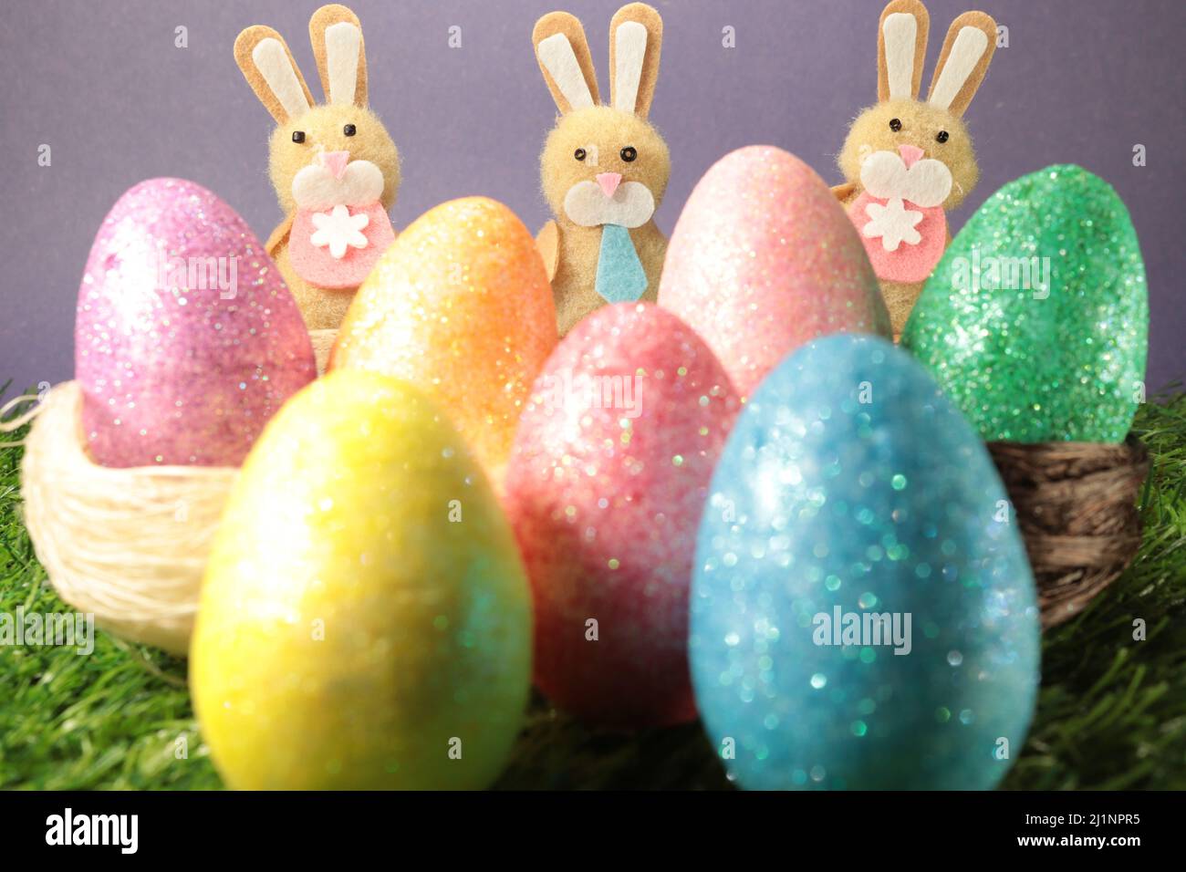 Three easter bunnies spaced evenly apart behind colorful easter eggs ...