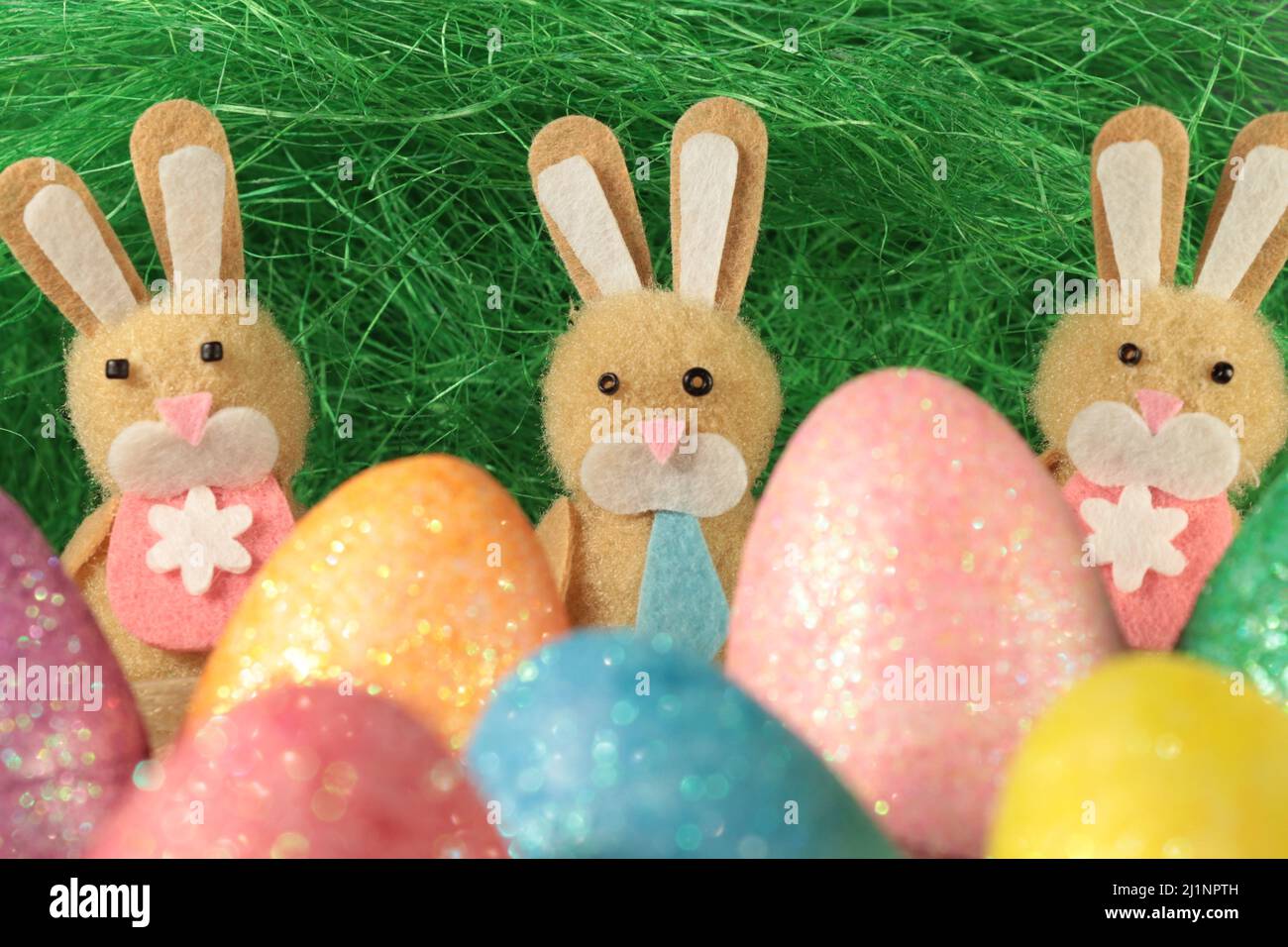 Three easter bunnies spaced evenly apart behind colorful easter eggs ...