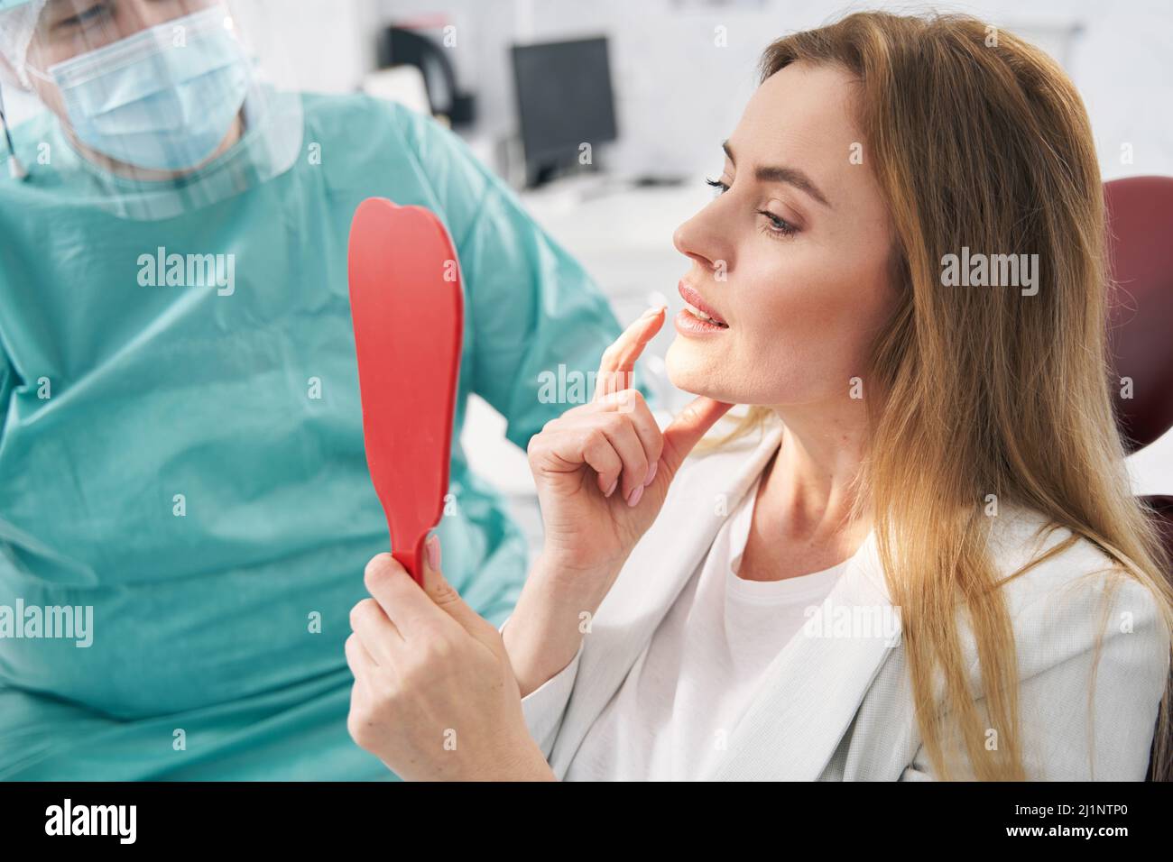Female patient looking in the mirror in dental clinic Stock Photo - Alamy
