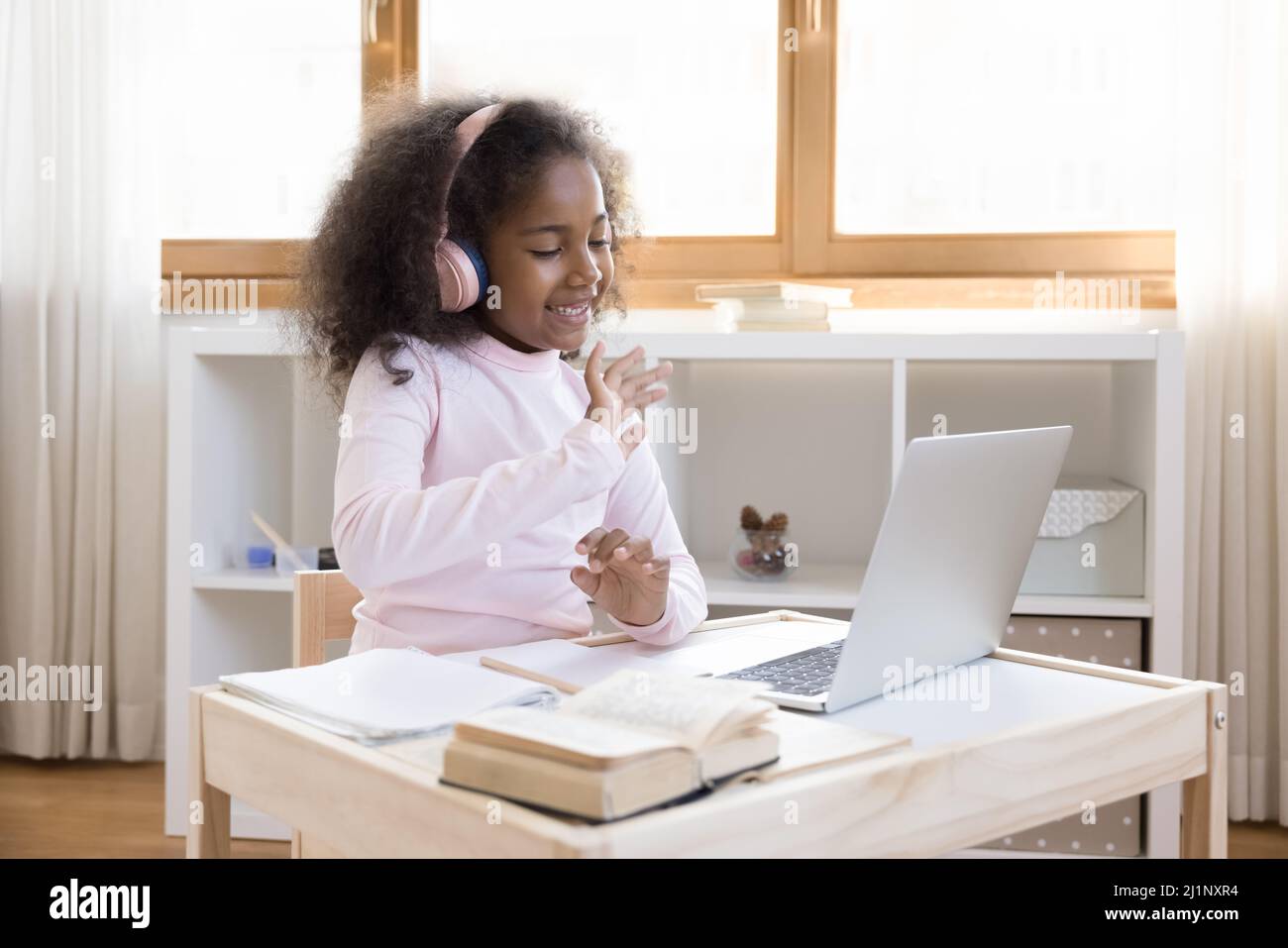 Cheerful African American little blogger girl wearing wireless pink ...