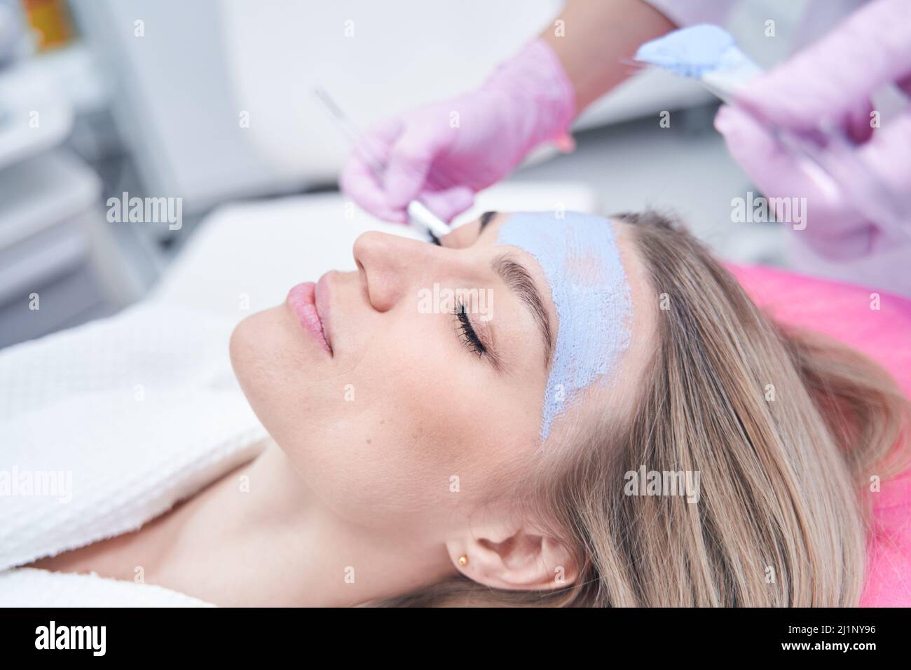 Calm spa client dozing during blue clay mask application Stock Photo ...