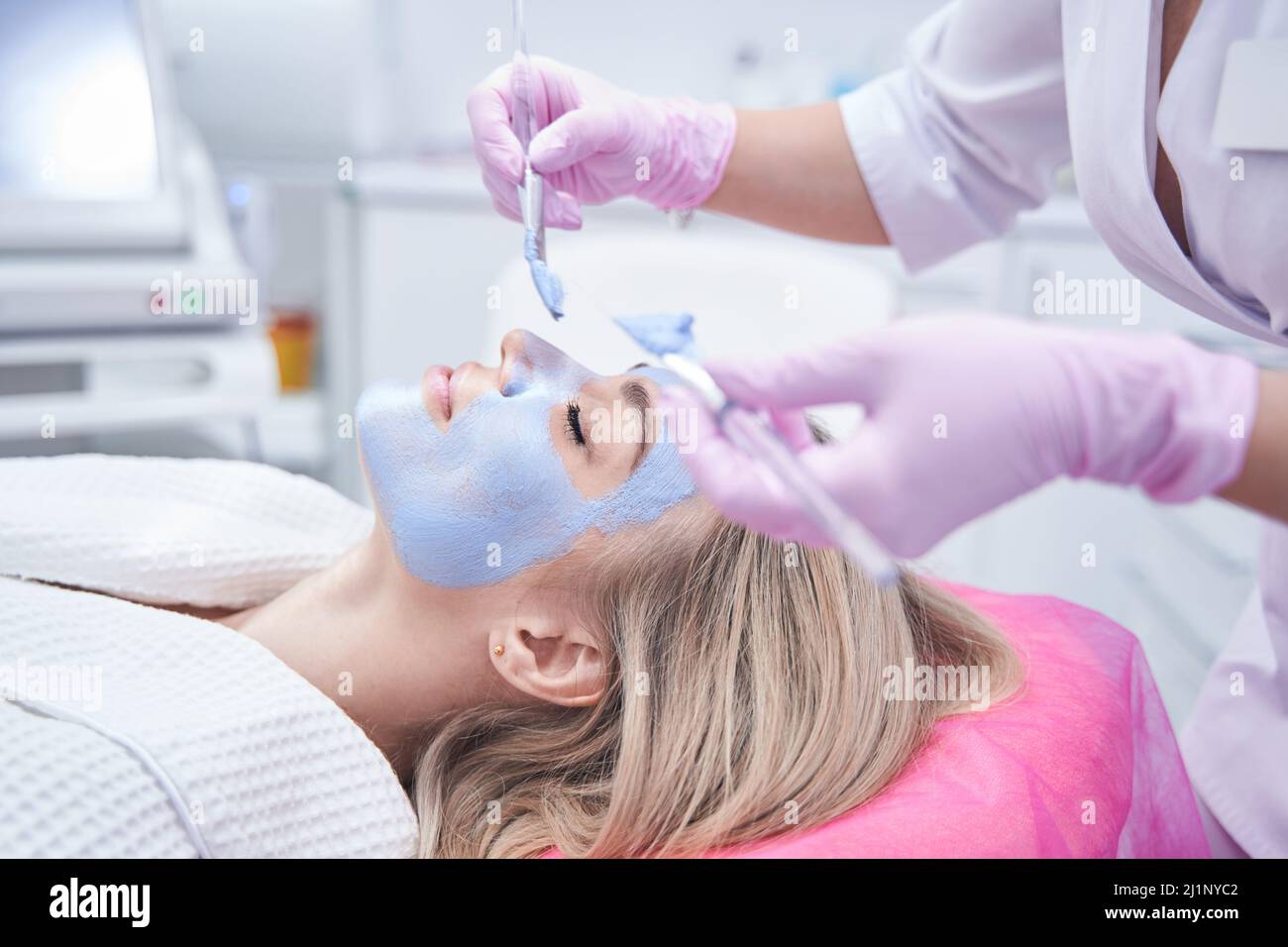 Cosmetician applying facial mask to skin of serene lady Stock Photo - Alamy