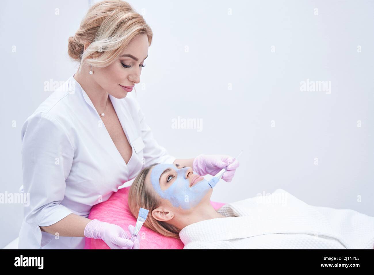 Concentrated skin doctor applying mask to face of patient Stock Photo ...