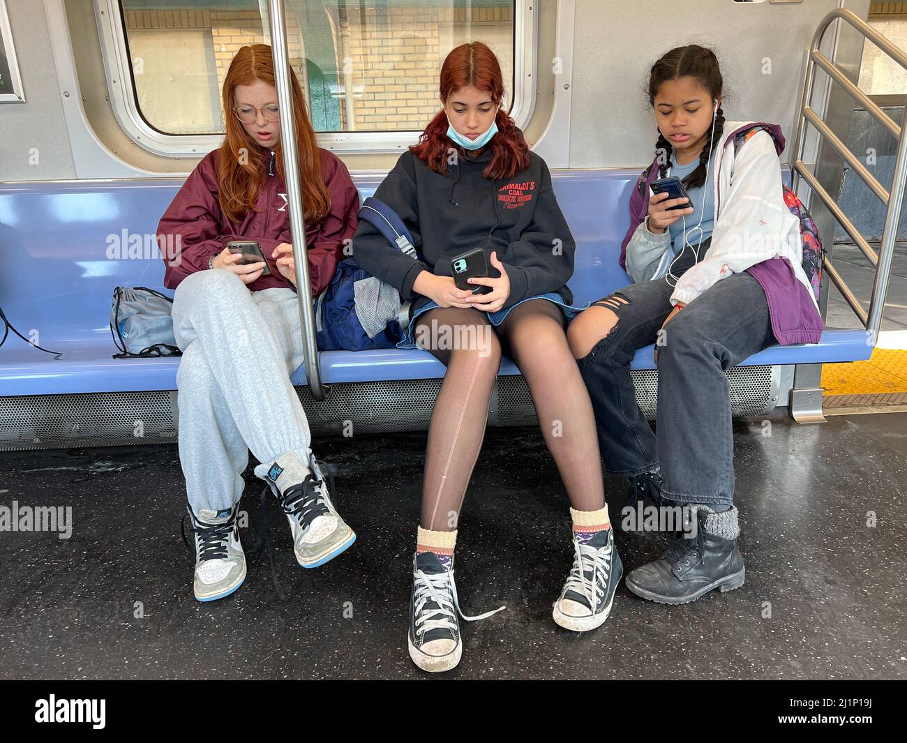 Three teenage high school students engrossed on their phones riding an ...