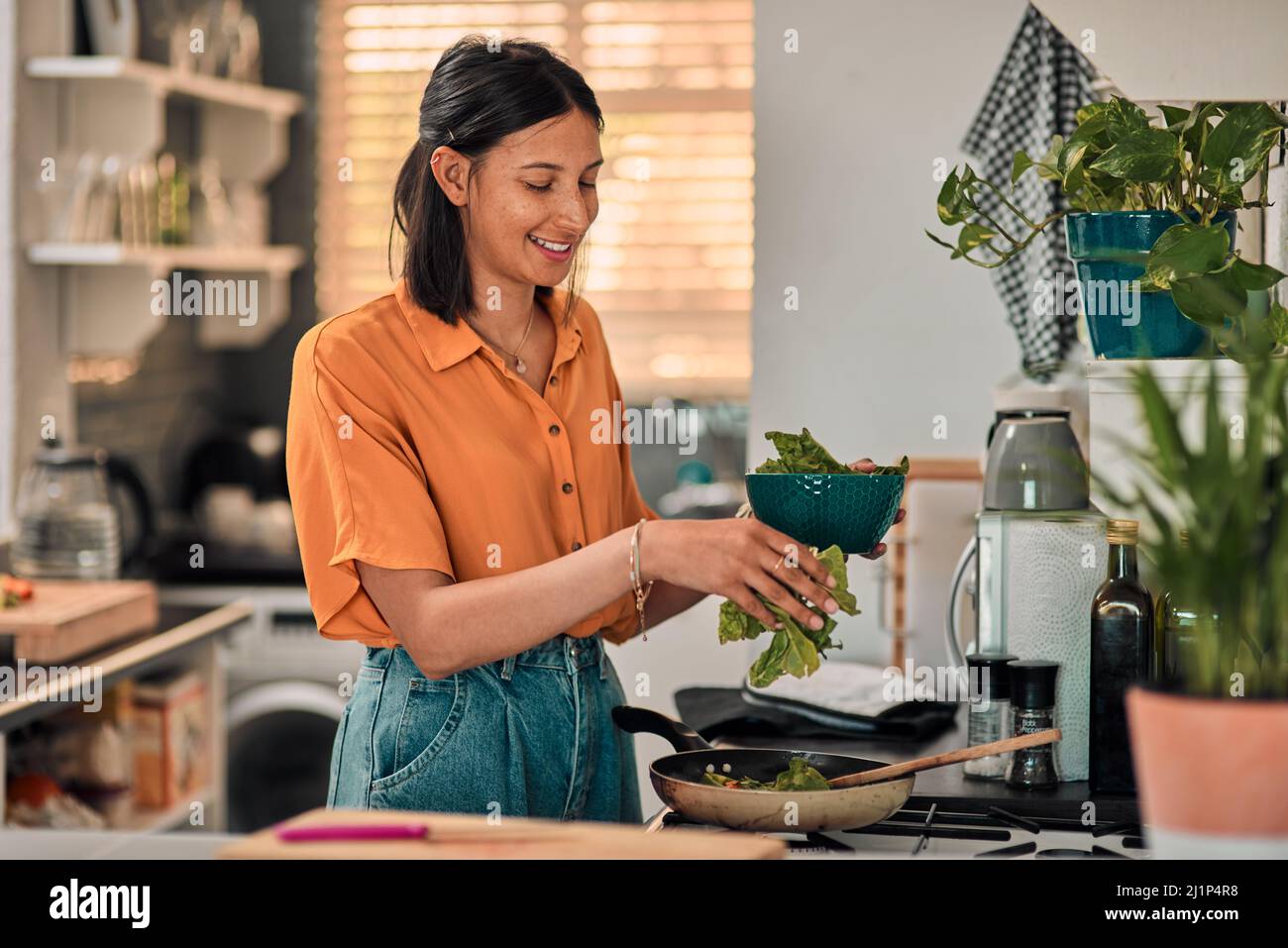 Leafy greens add goodness to any meal. Shot of a happy young woman ...