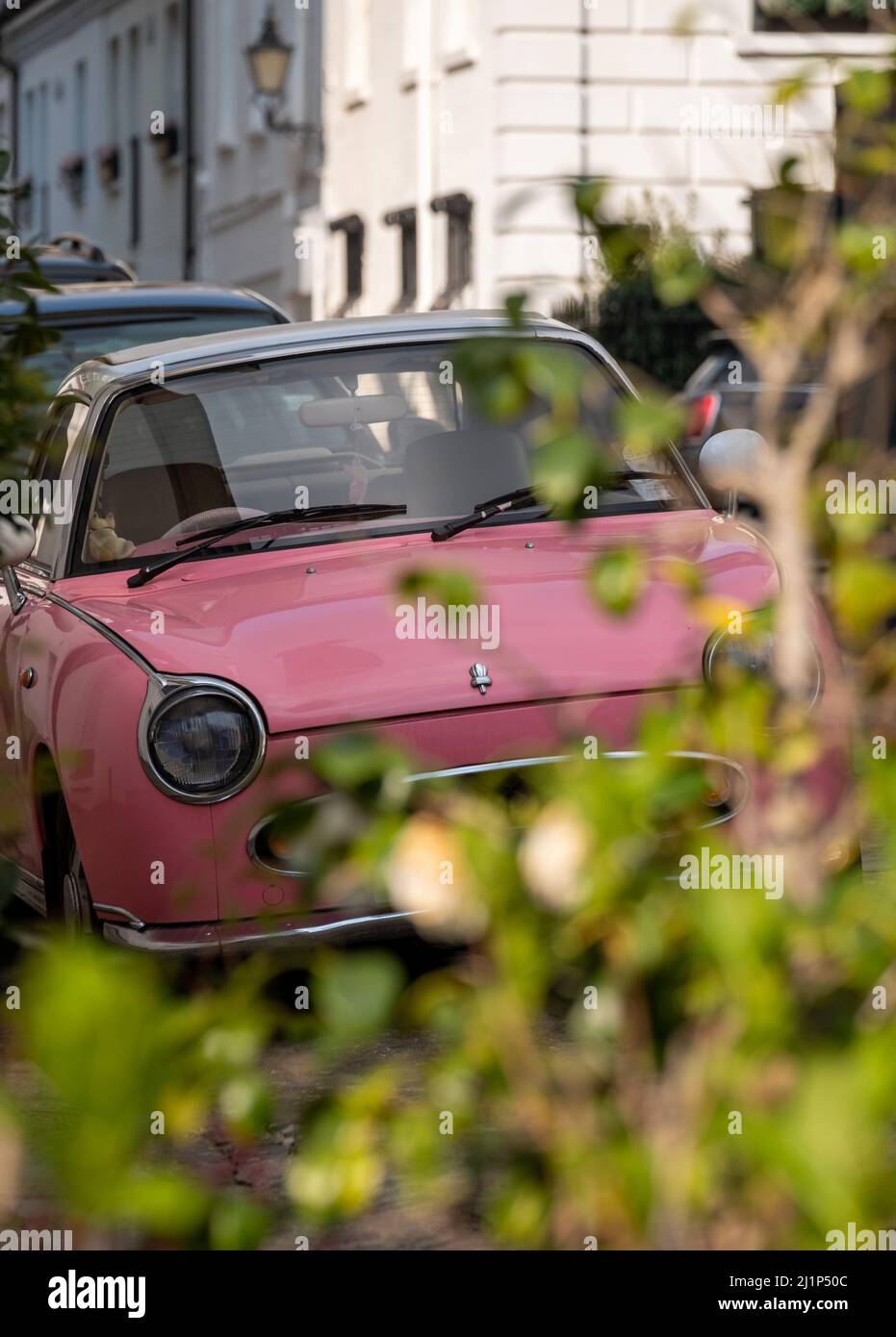 Cute pink Nissan Figaro retro style car, parked in a mews street in ...