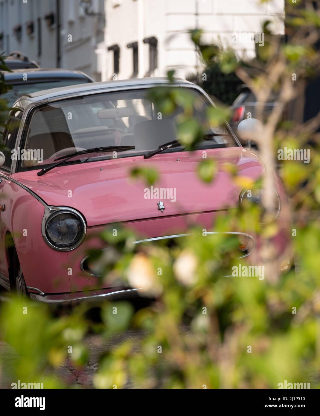 Cute pink Nissan Figaro retro style car, parked in a mews street in ...