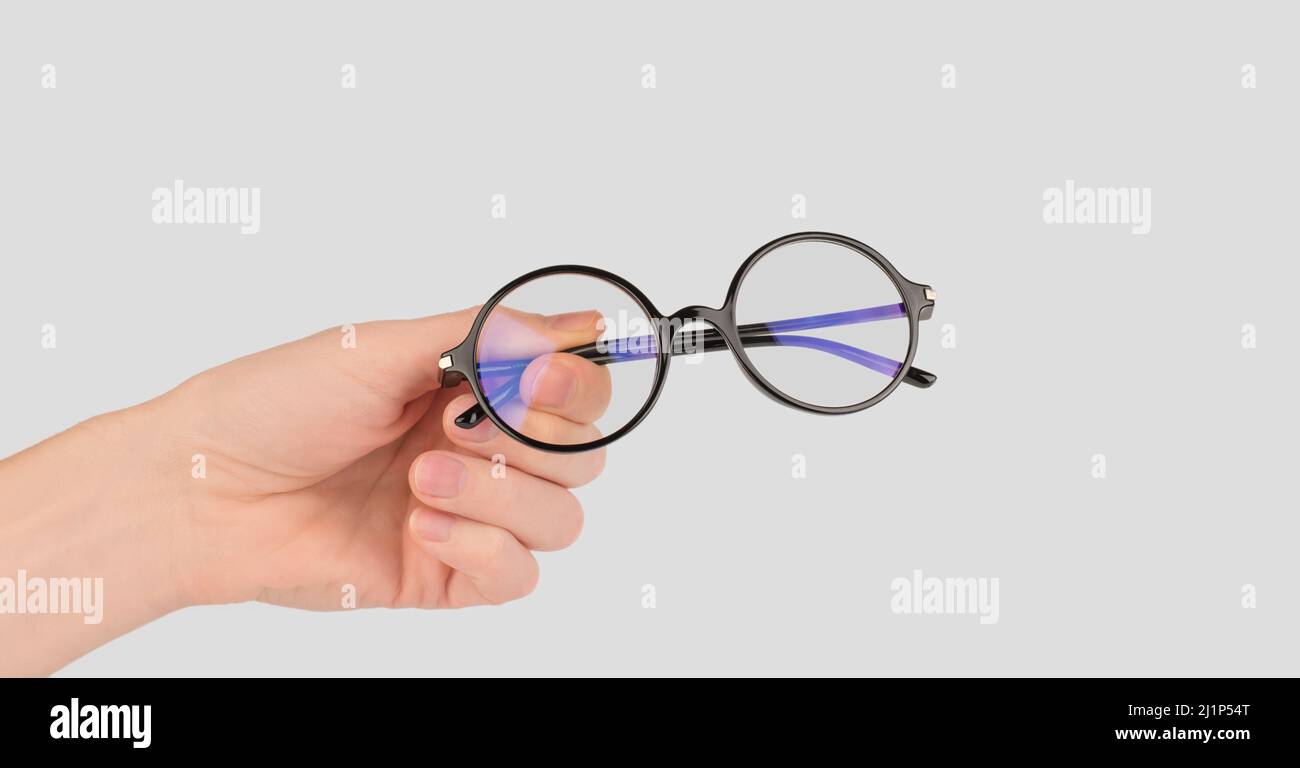 Round stylish glasses for vision in a male hand on a gray background ...