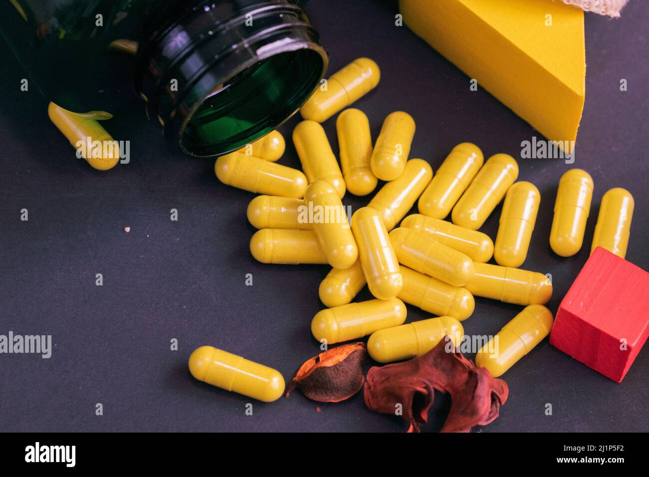 A closeup shot of a green bottle of supplements with yellow capsules ...
