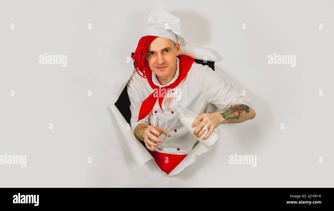 Man with red dreadlocks holds it in his hand milk. Confident young cook ...
