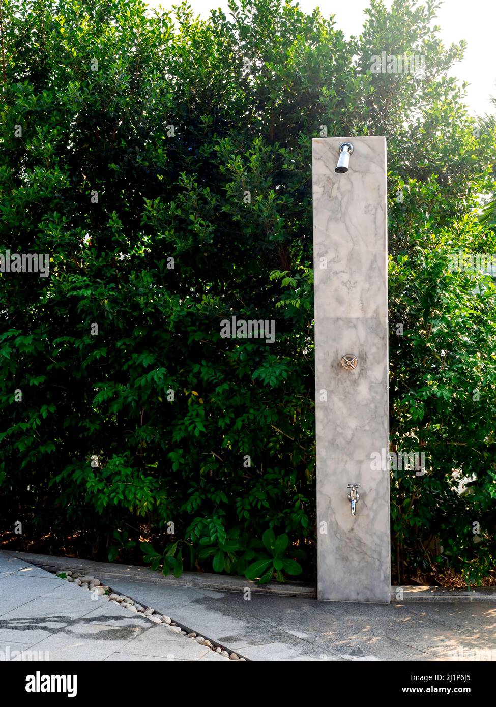 Outdoor shower on a marble pole near the tree and green leaves ...