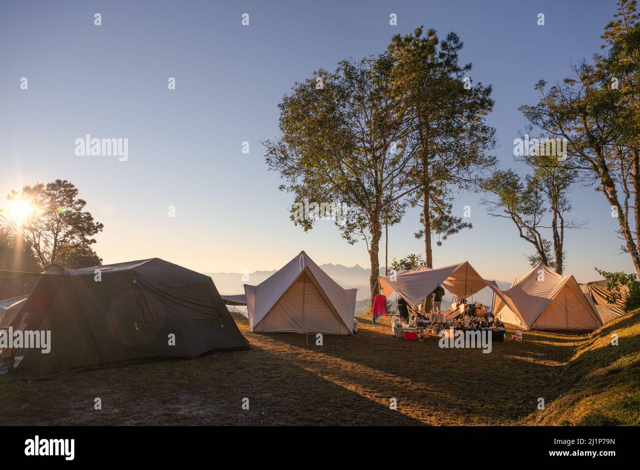 Tents camping in campsite on hill with sunrise over mountain at ...