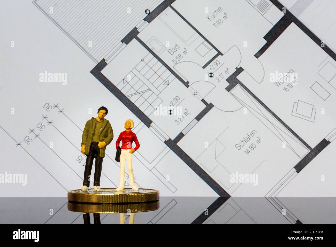 To miniature figures standing on a house blueprint as if discussing the ...