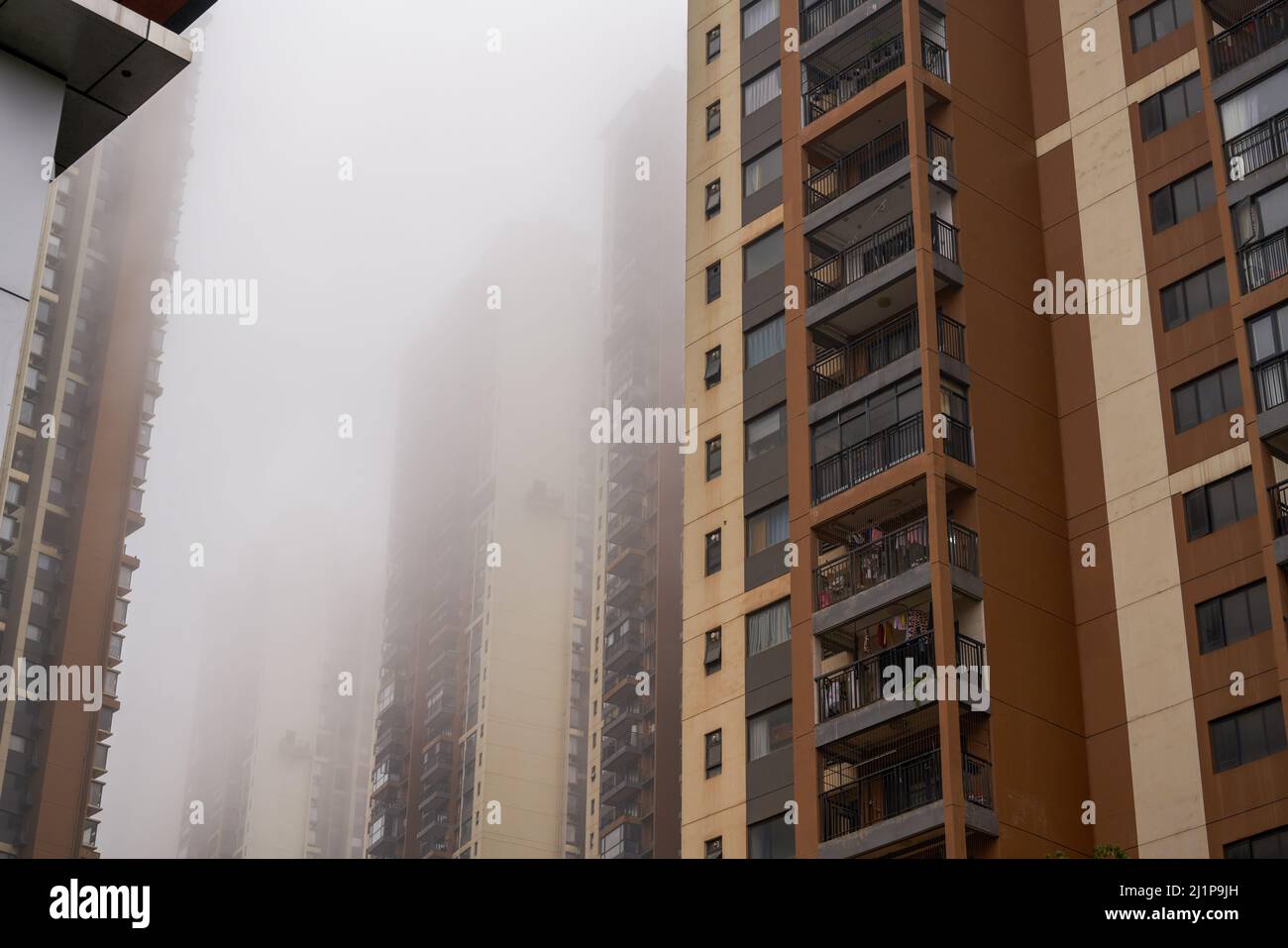 Urban residential high-rise buildings in dense fog in rainy weather ...