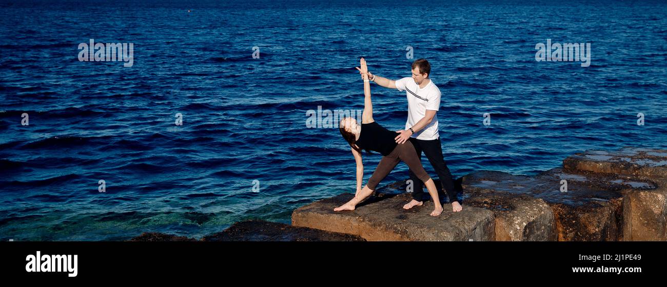 Personal trainer man correct woman client while doing stretching or ...