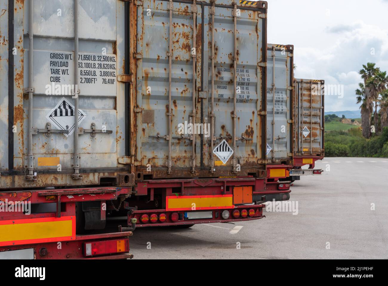 Rear view of several trucks with containers labeled with dangerous ...