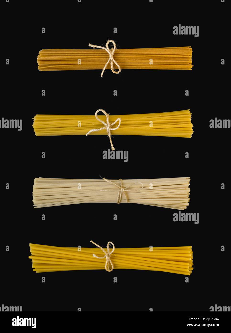 Variety of spaghetti tied with jute string, isolated on black surface ...
