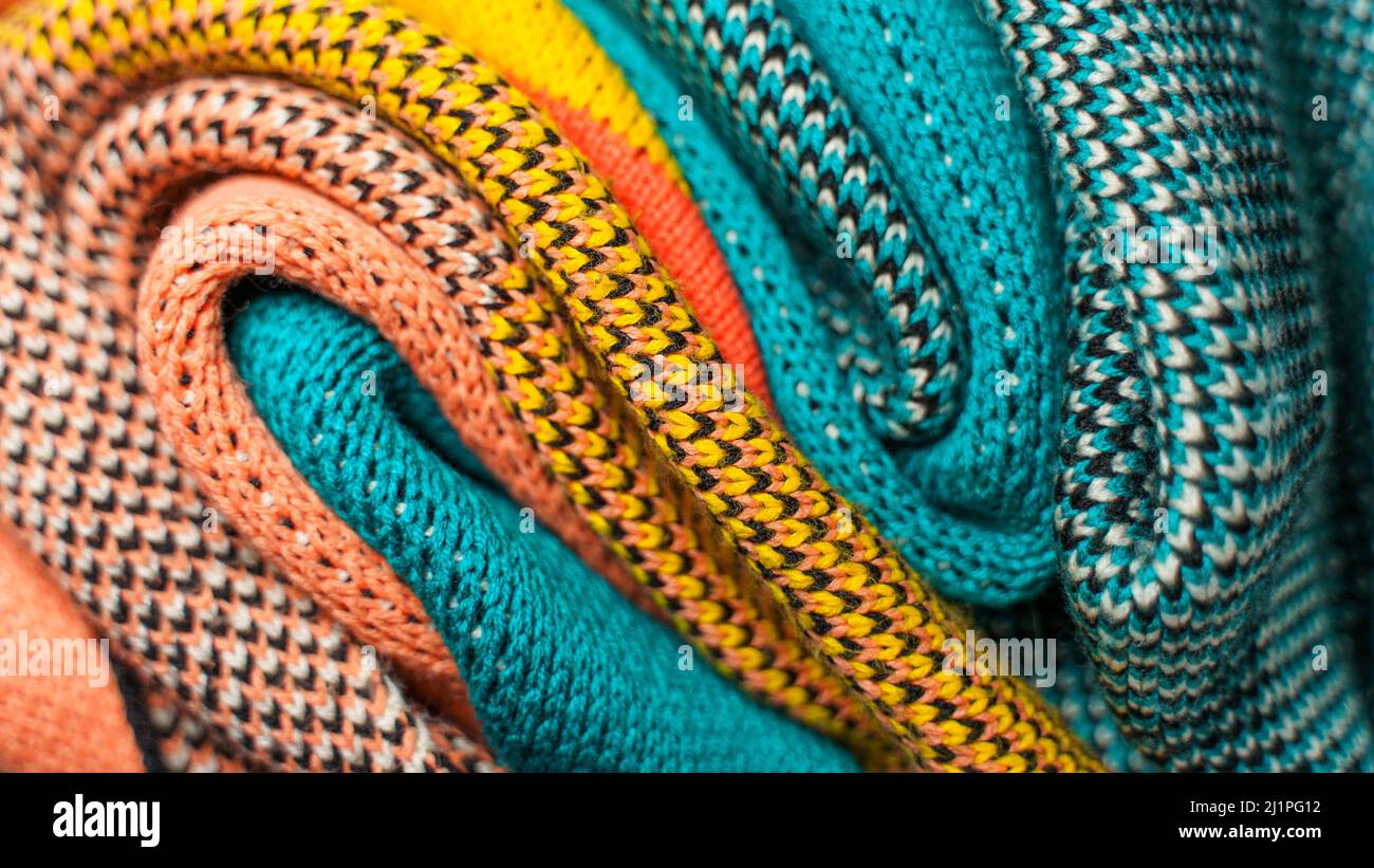 Twisted folds of colorful knitted fabrics of winter clothes with ...