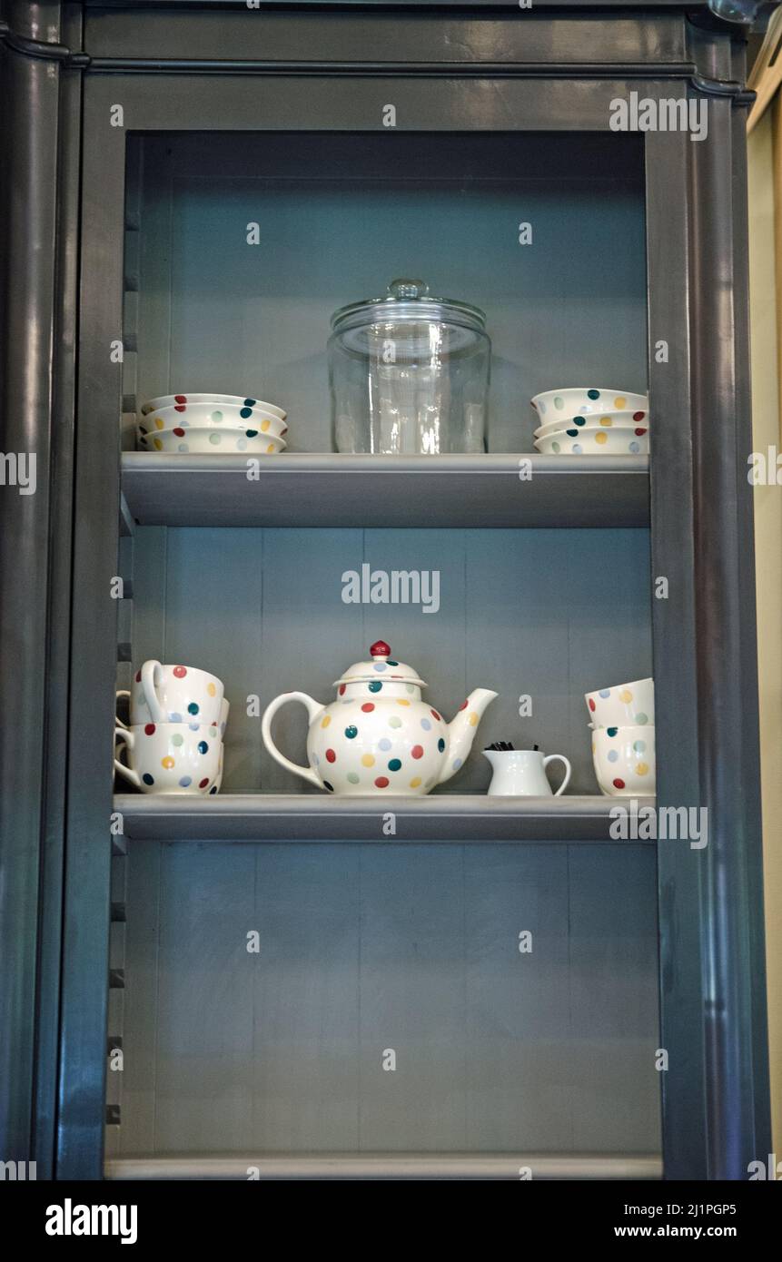 Crockery on display in a wooden painted cupboard on a kitchen wall ...