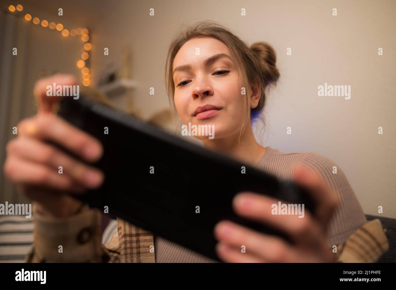 Close-up. A pretty girl is playing on a portable game console in the ...