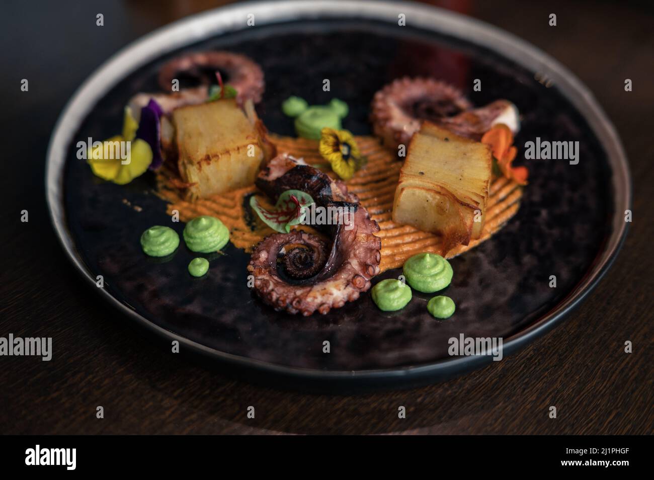 Octopus with potatoes on pea mash decorated with edible flowers Stock ...