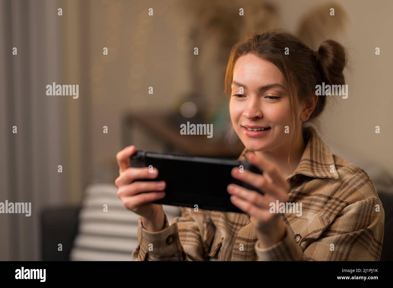 A fair-haired girl with a portable game console in her hands. Mobile ...